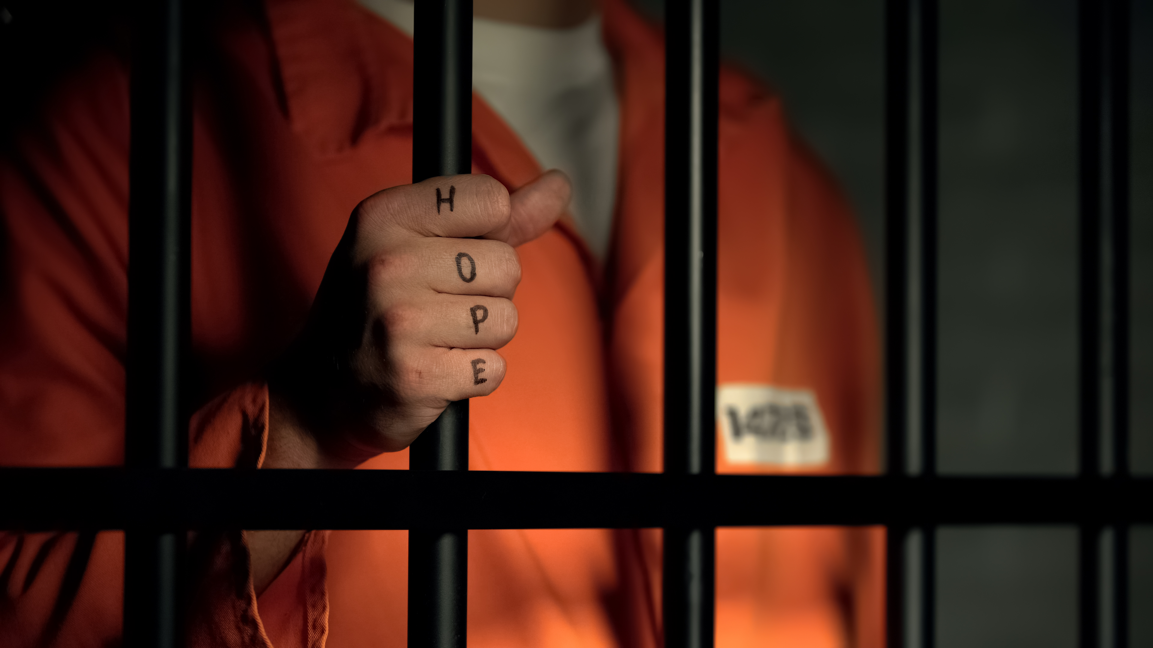Hope word on imprisoned man fingers, holding jail bars, dream about ...